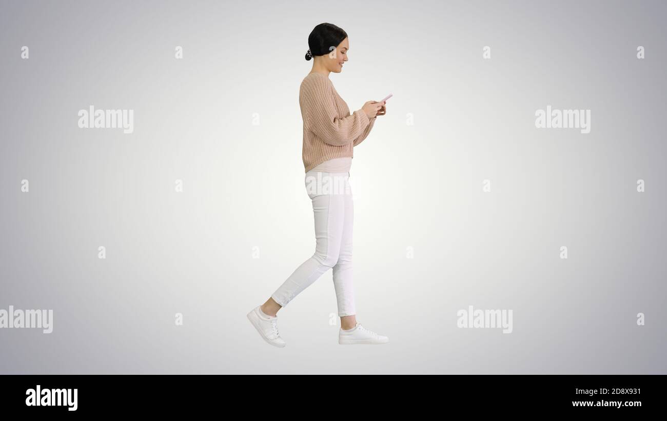 Wide shot. Side view. Pretty young female texting on mobile phone while ...