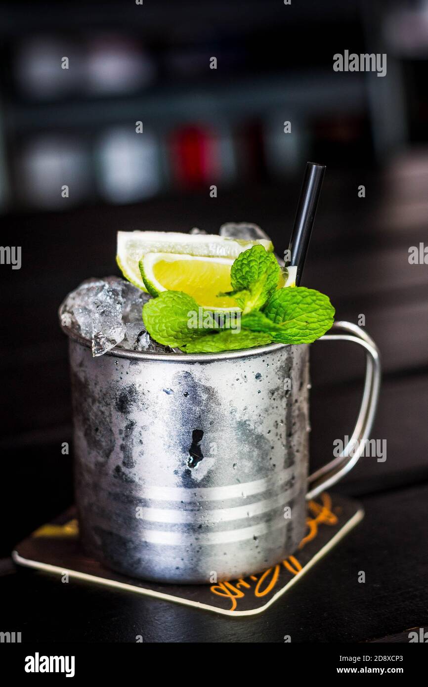 a cocktail served in a metal mug with ice, a lemon wedge and mint Stock ...