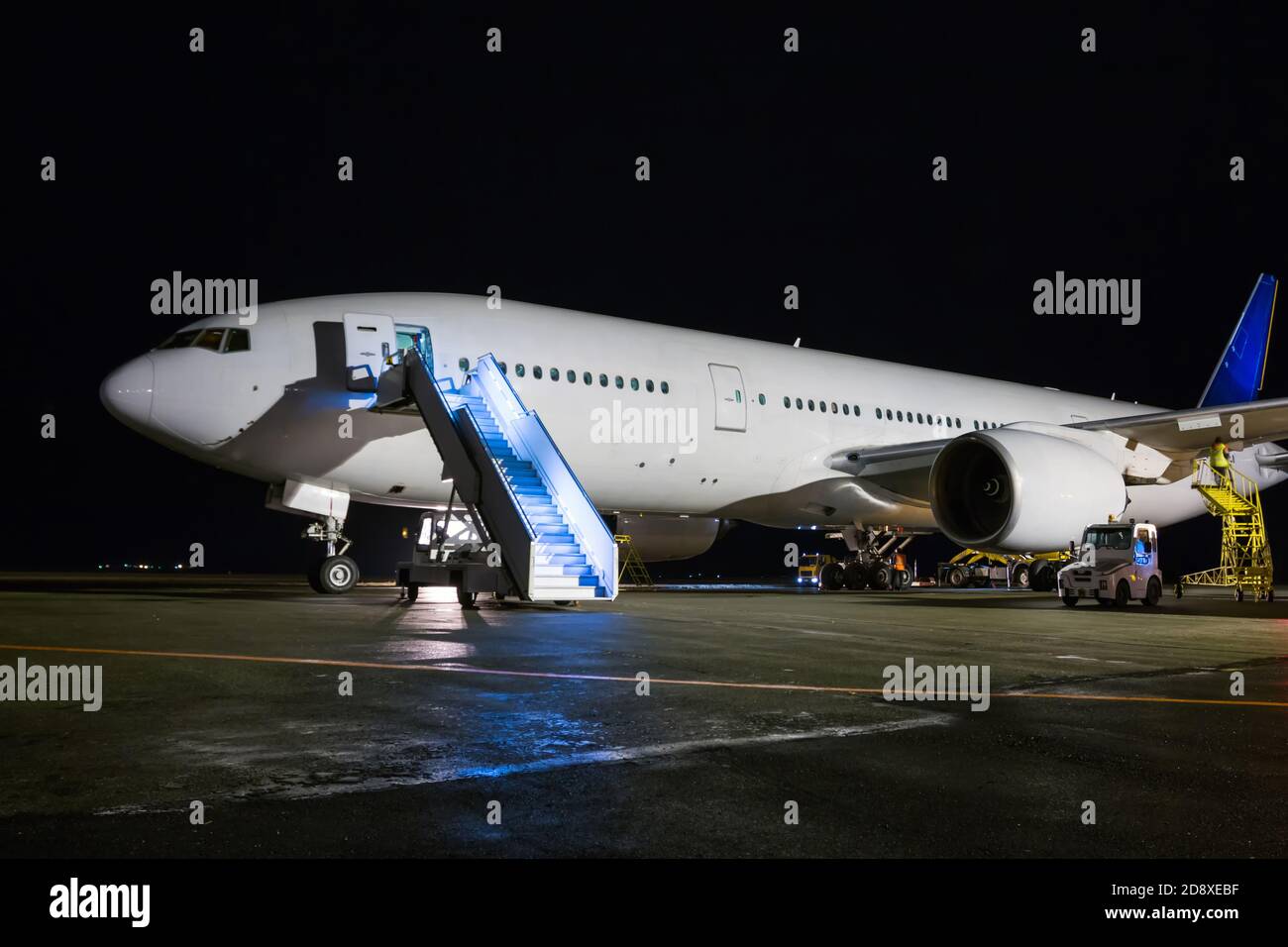 Wide body passenger airplane with boarding ramp at the night airport ...