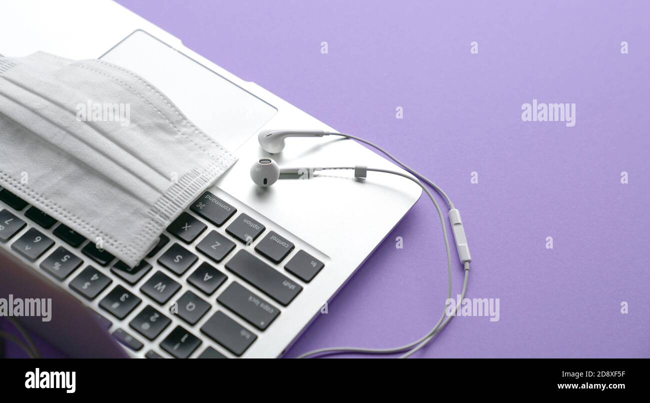 Ear phones on top of computer laptop with face mask. Work from home ...