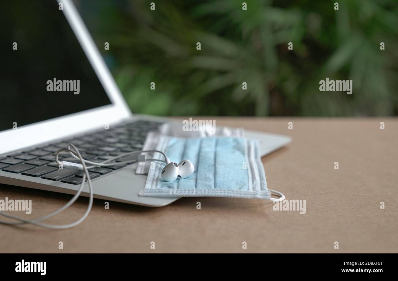 Ear phones on top of computer laptop with face mask. Work from home ...
