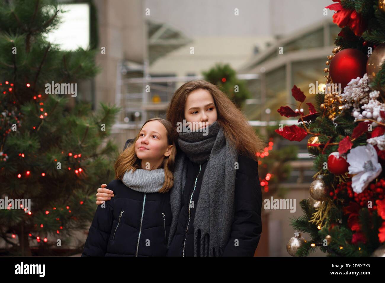 Two cheerful girls are having fun outdoor at Christmas market. Happy ...