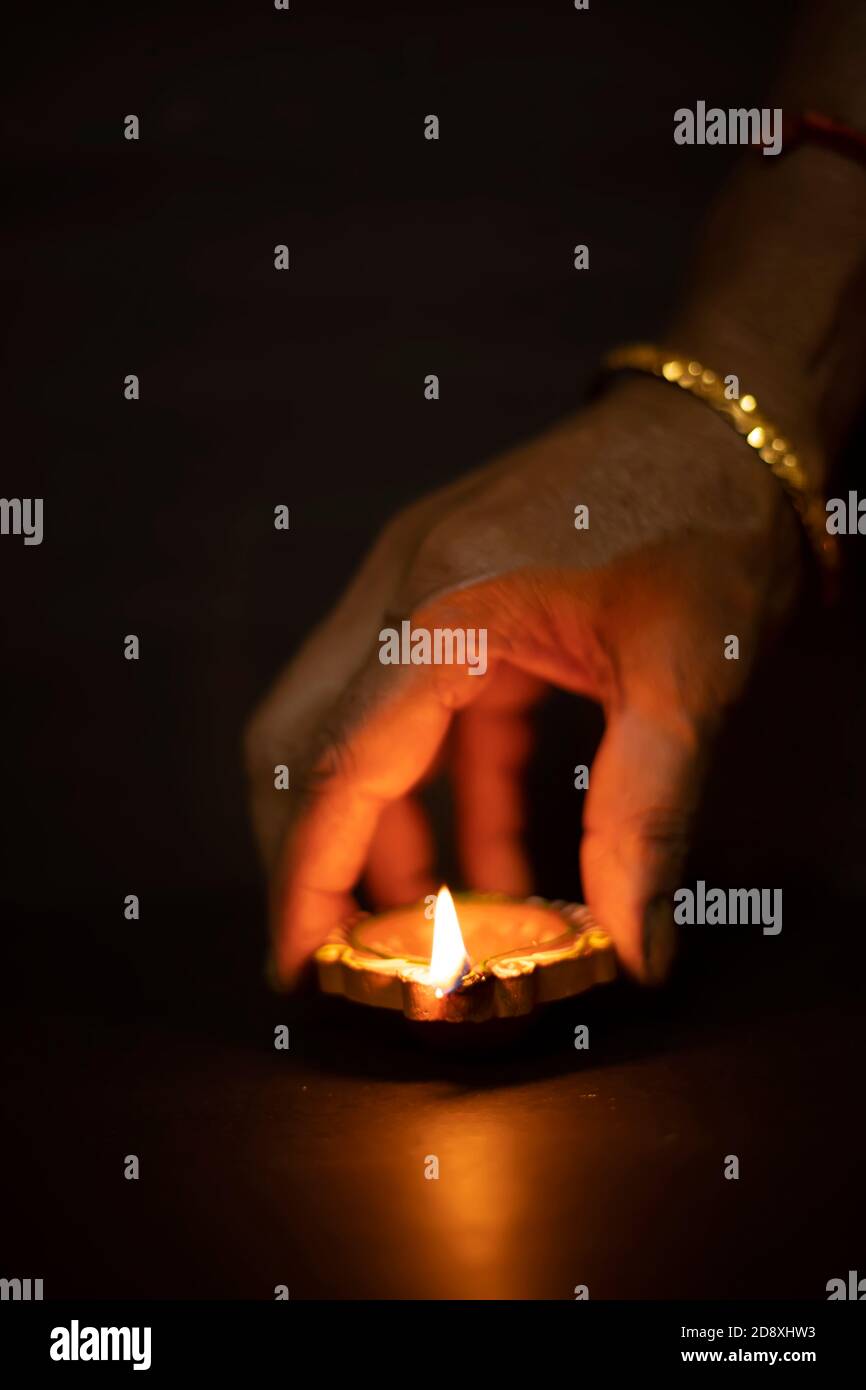 Happy diwali - Hand holding or lighting or arranging diwali diya or ...