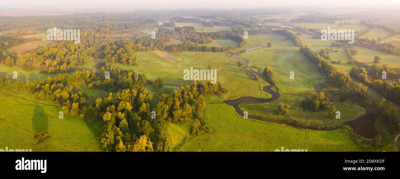Fresh green landscape with forests, meadows and river illuminated by ...