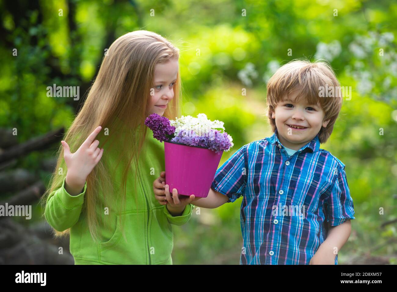 Cute children gardening and planting flowers to the ground in spring ...