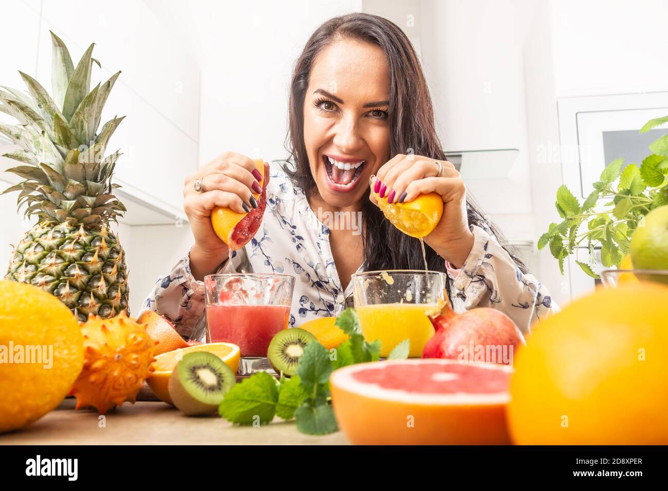 Female squeezing red and yellow orange into a fresh juice Stock Photo ...