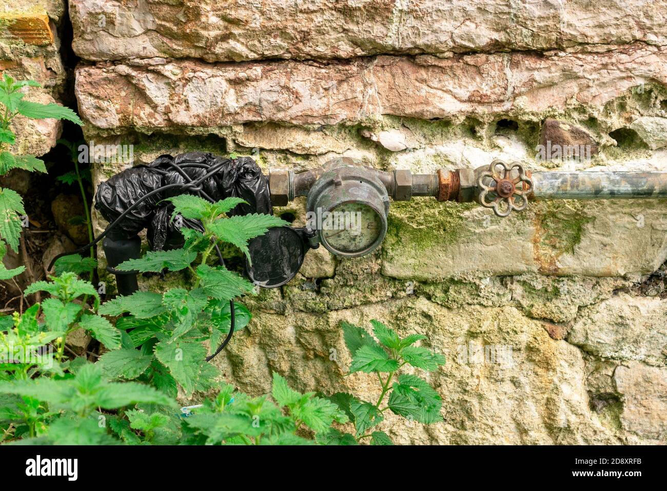 old rusty plumbing meter, pipe and valve on destroyed stone wall Stock ...