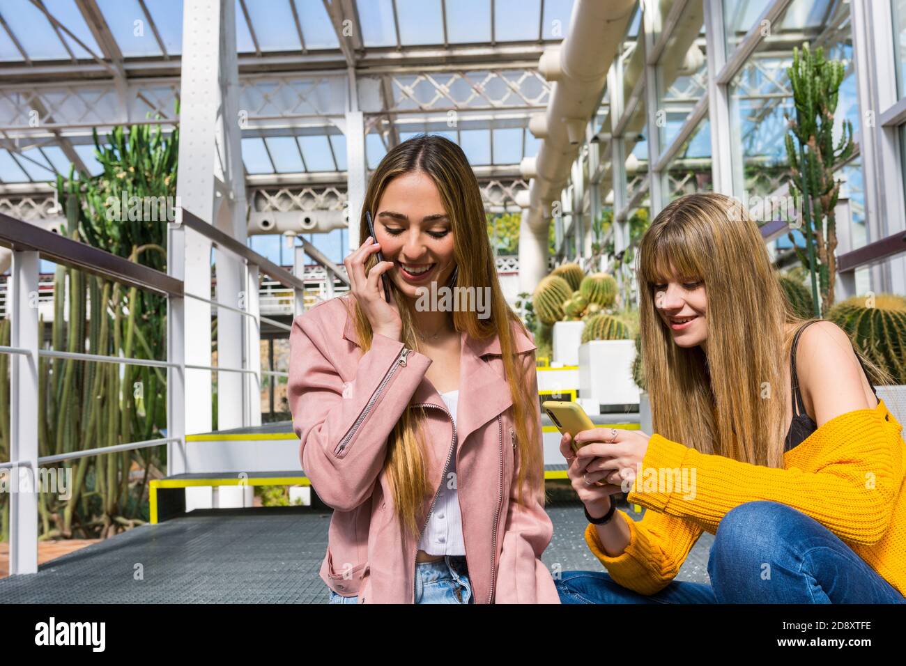 Two friends interacting with their mobile phone while talking and ...