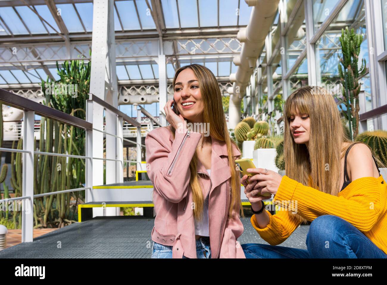 Two friends interacting with their mobile phone while talking and ...