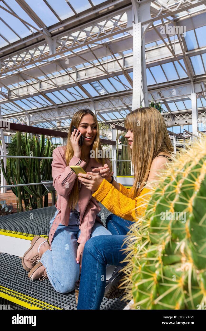 Two friends interacting with their mobile phone while talking and ...
