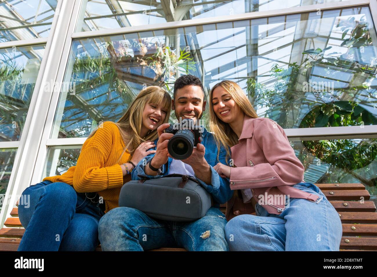 Group of friends looking at photos taken with a reflex camera in a park ...