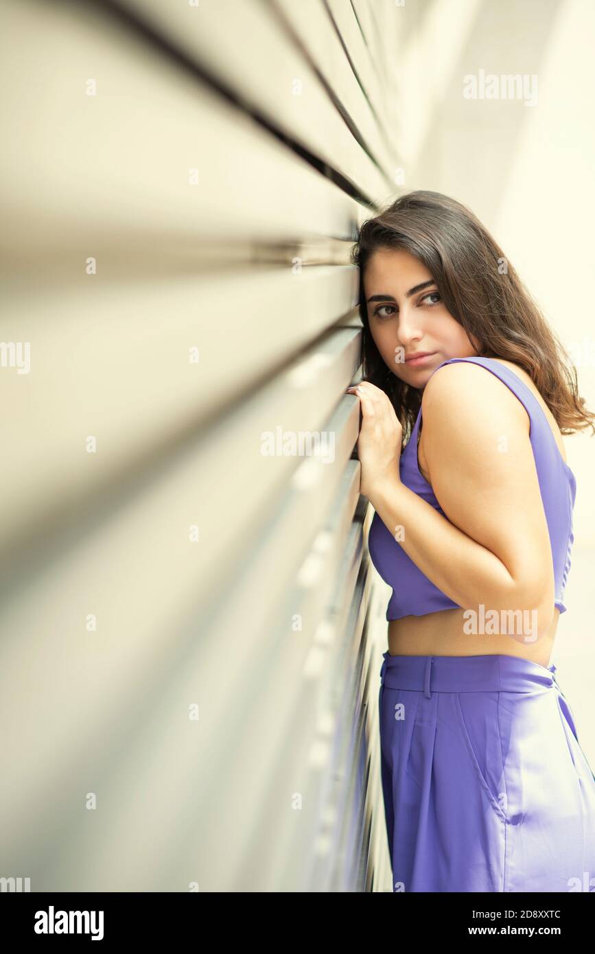 Scared young woman leaning against wall looking away outdoors Stock ...