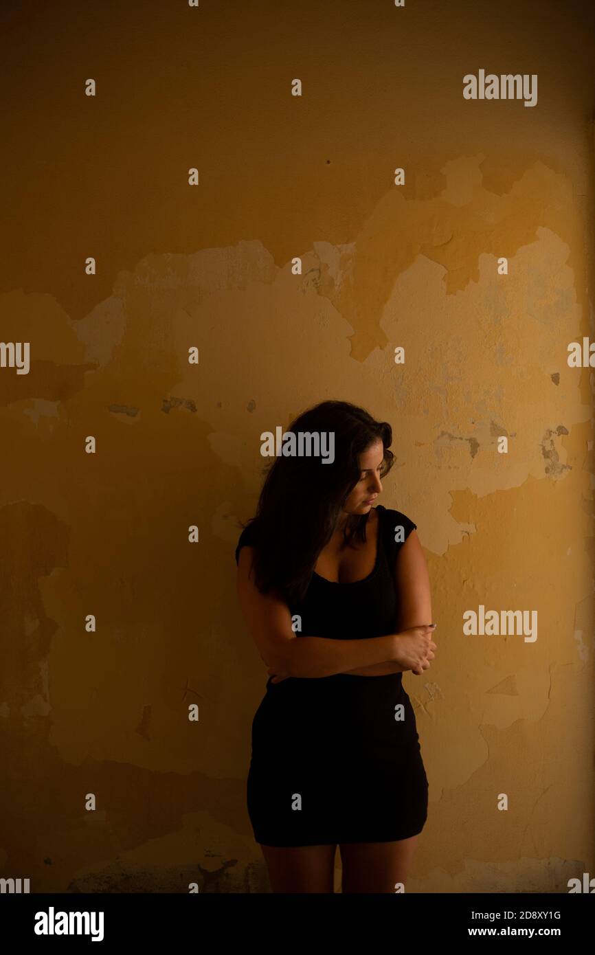 Woman in short dress standing inside derelict building looking away ...