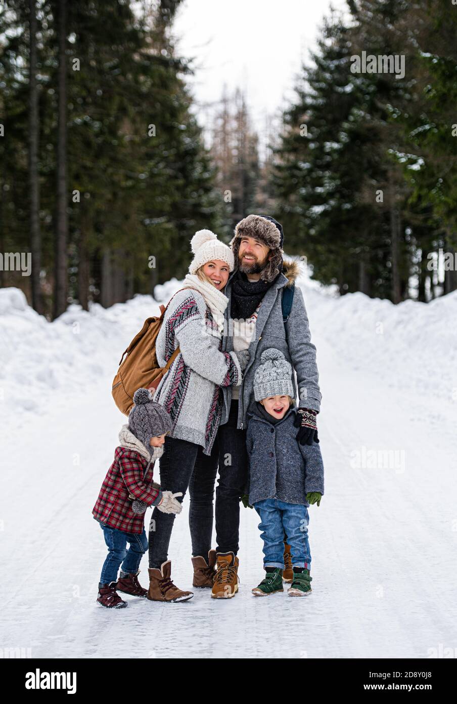 Father and mother with two small children in winter nature, standing in ...