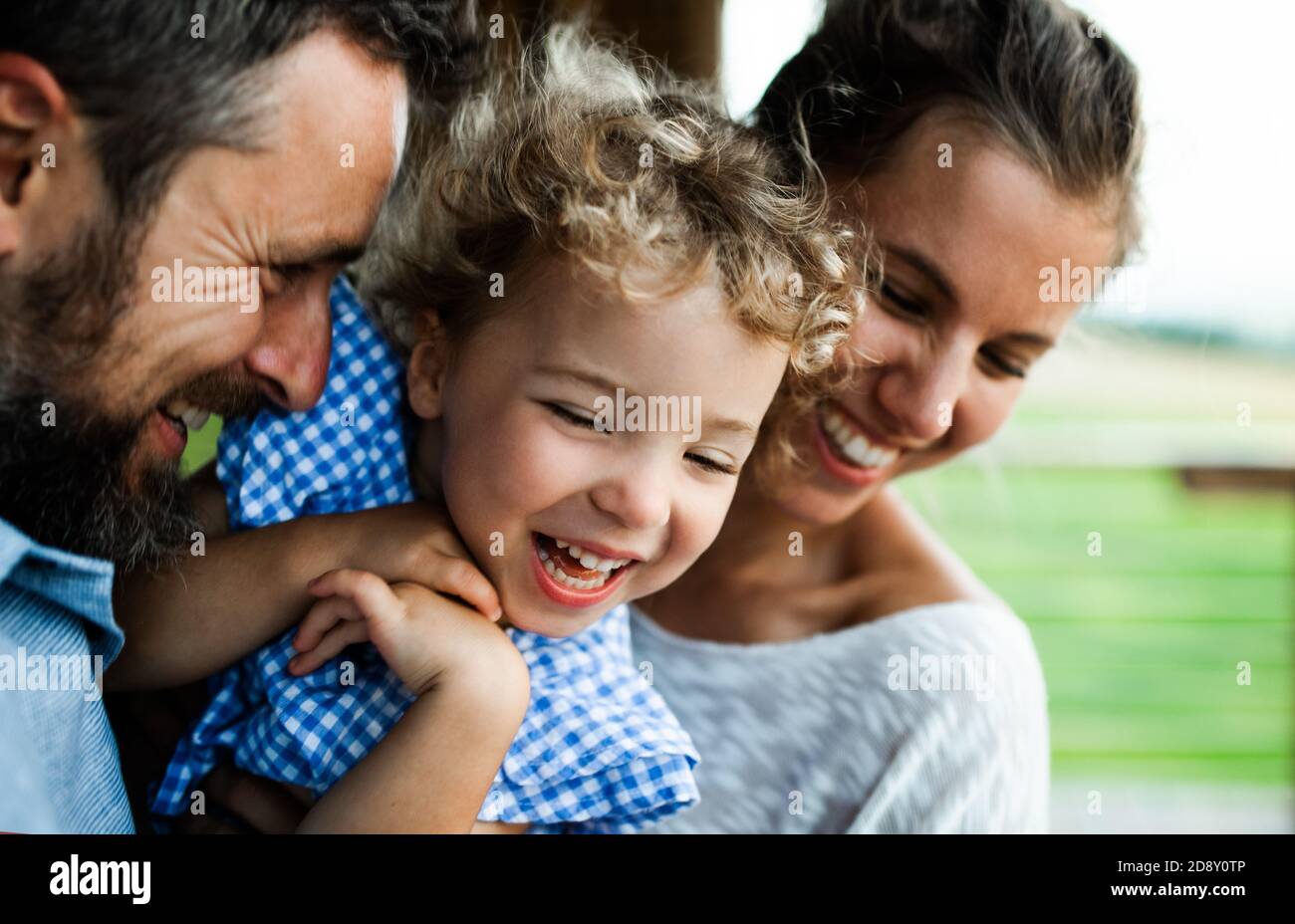 Close-up portrait of family with small daughter by wooden cabin ...