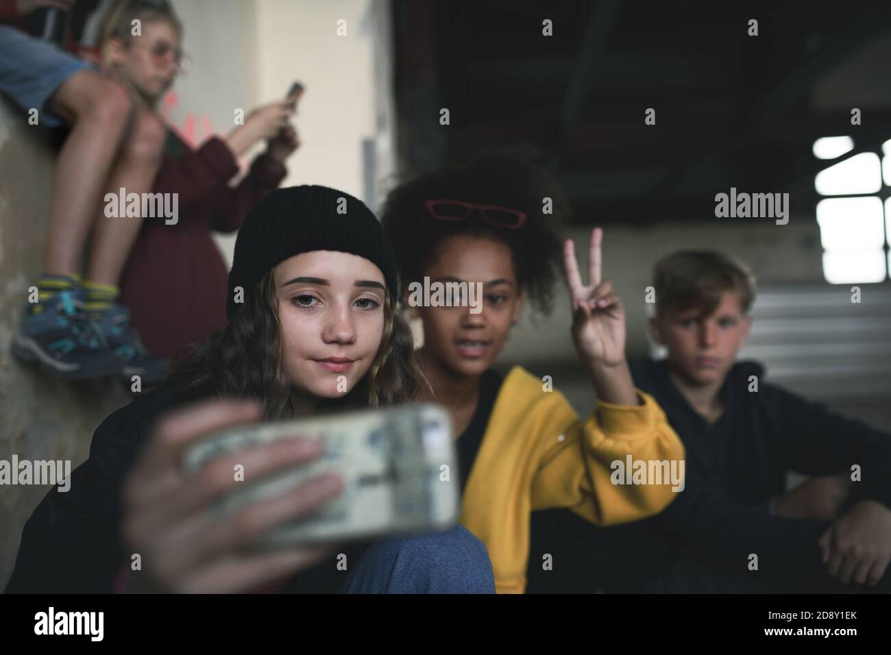 Group of teenagers gang sitting indoors in abandoned building, taking ...