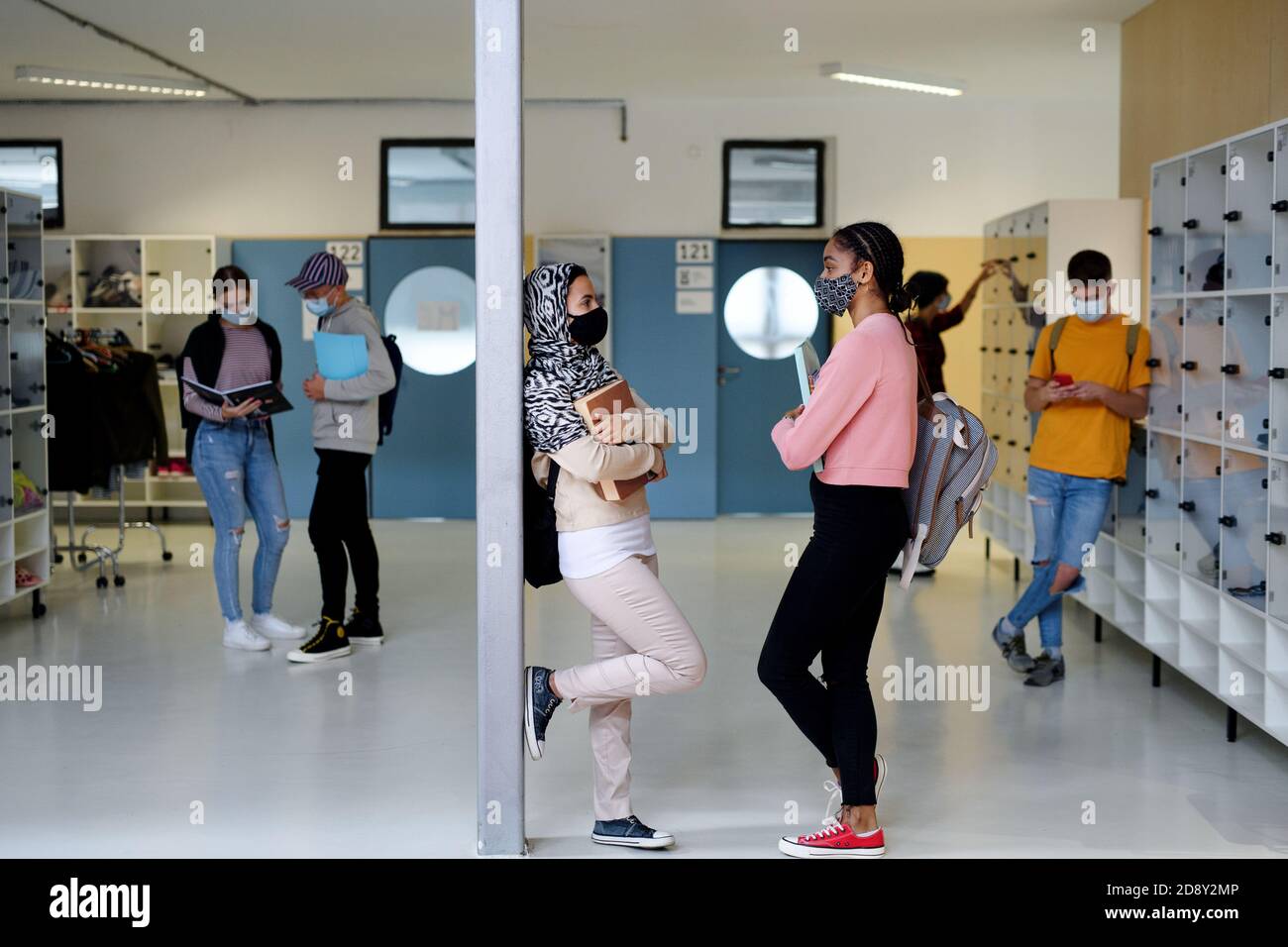 Young students friends with face masks back at college or university ...