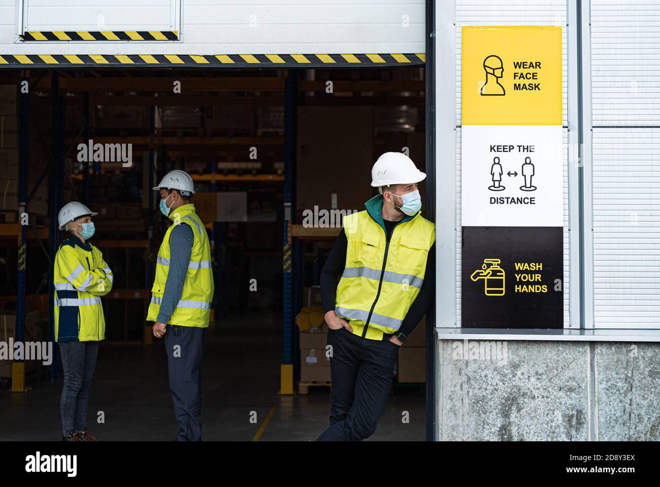 Group of workers with face mask talking in front of warehouse ...