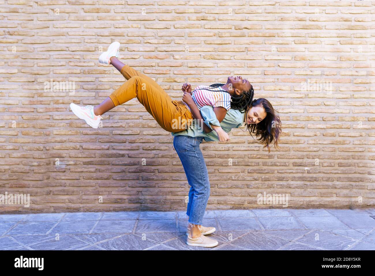 Funny multiethnic woman carrying her best friend piggyback Stock Photo ...