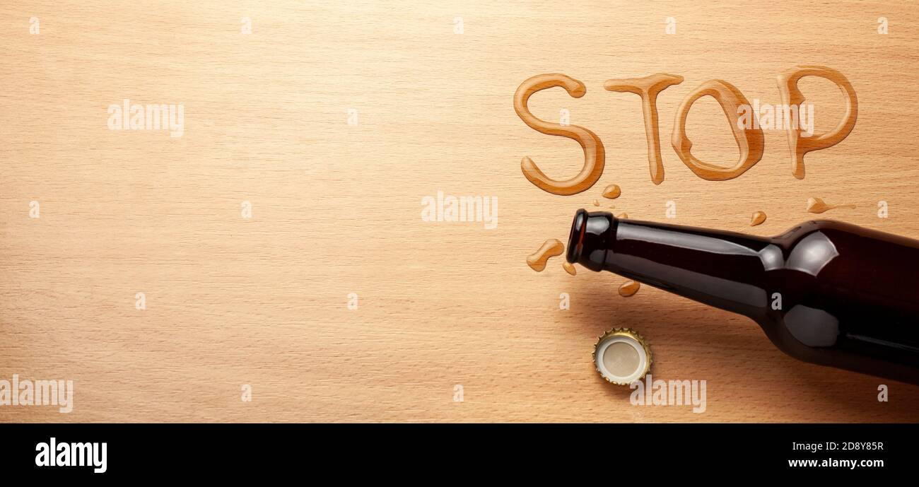 Beer bottle and spilled beer in the shape of the word STOP. Ban alcohol ...