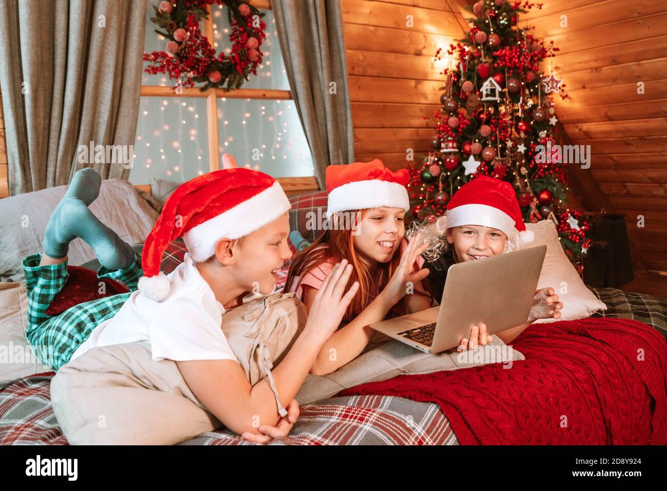 three children in pajamas on the bed having video chat with family on ...