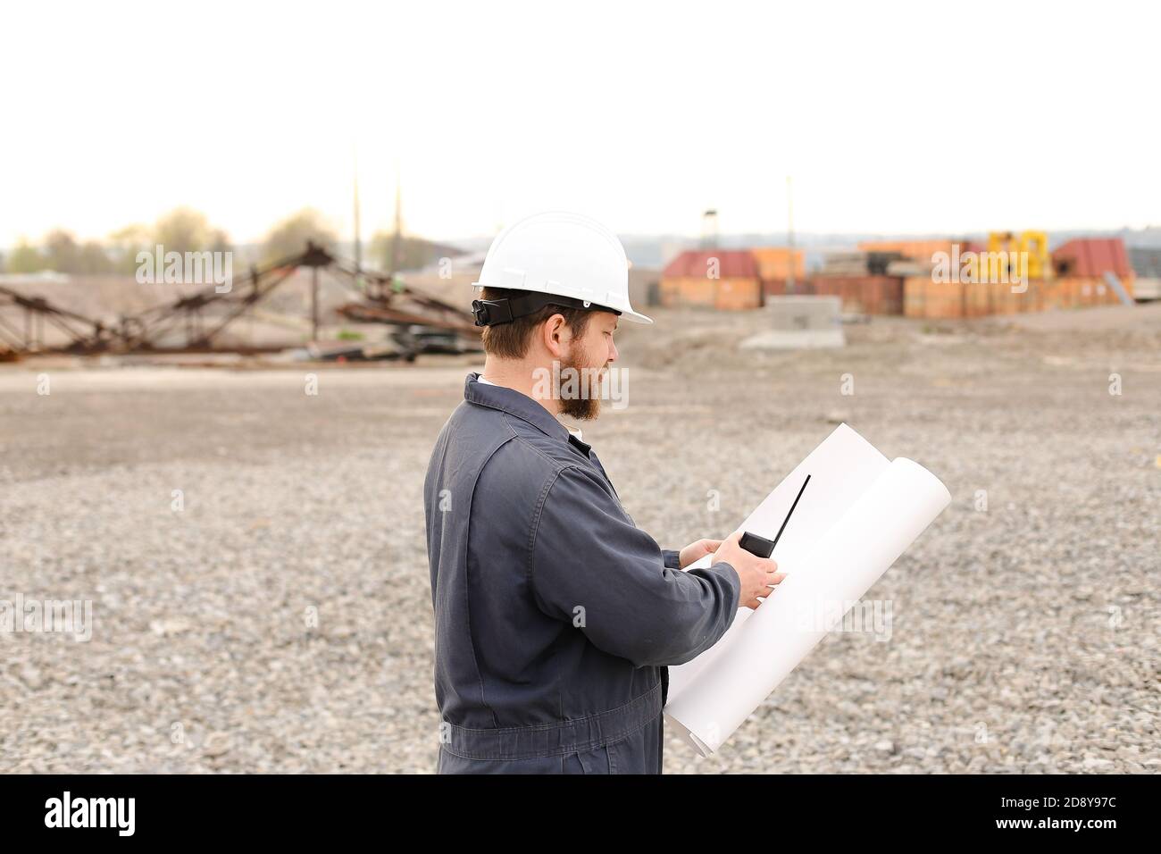 Back view of building engineer standing on construction site, talking ...