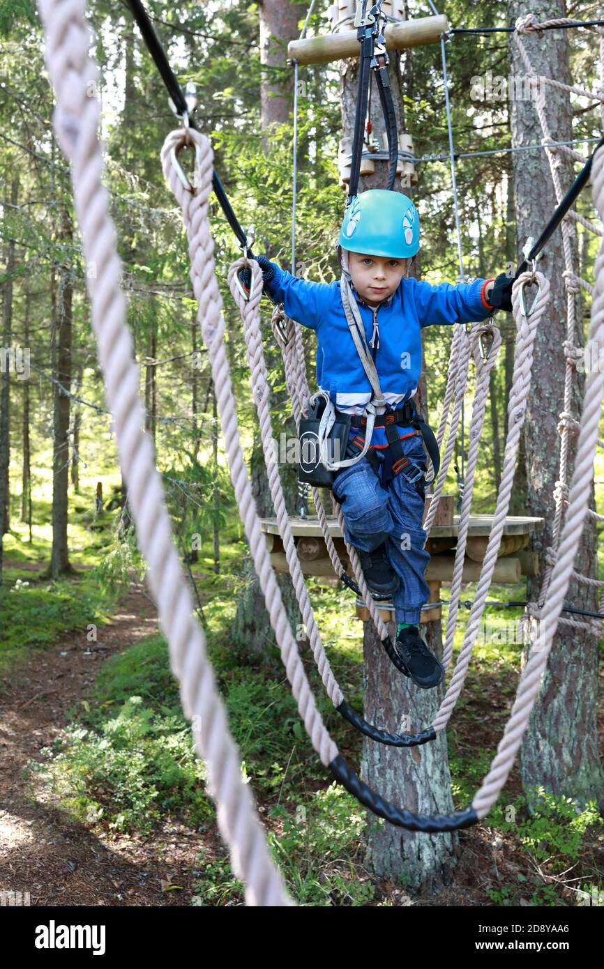 Boy overcoming hanging ropes obstacle in adventure park, Karelia Stock ...