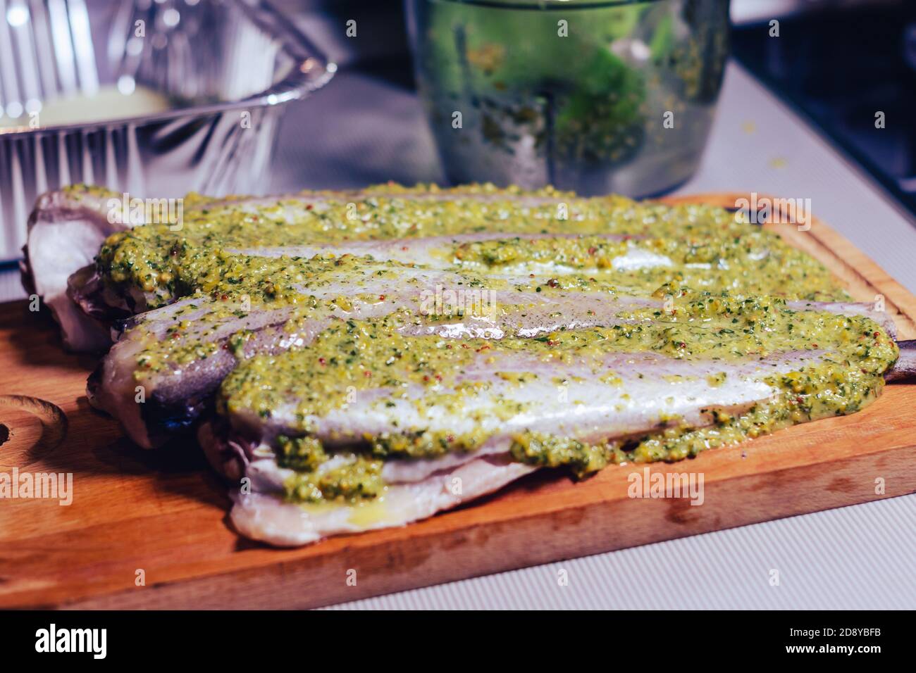 Raw pollock fillet with green sauce on a wood cutting board in the ...