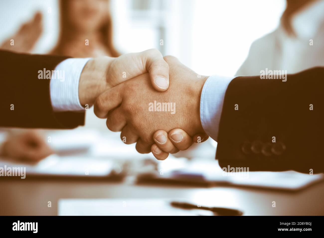Business people shaking hands at meeting while theirs colleagues ...