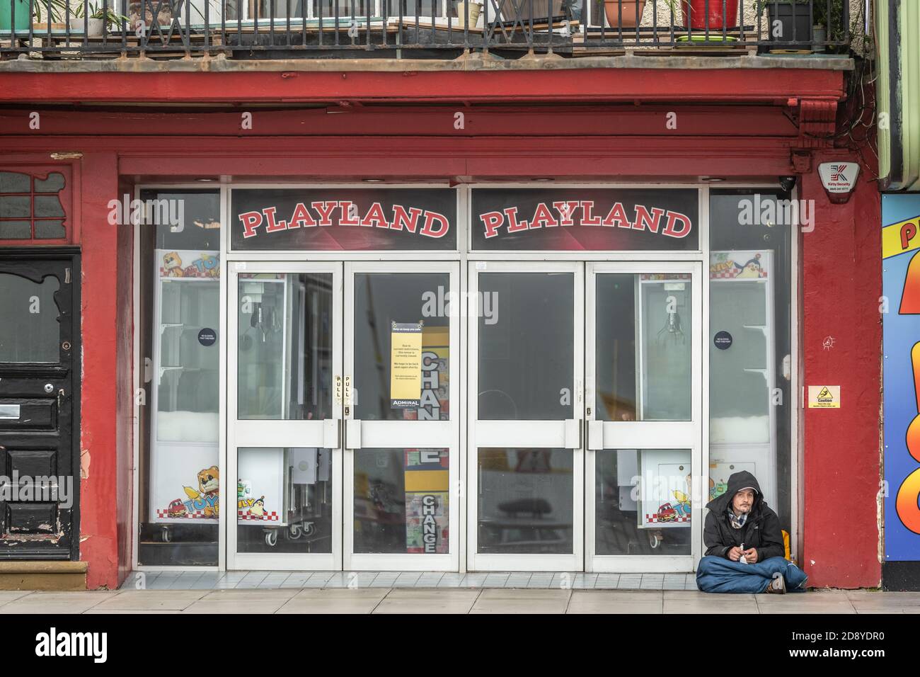 A homeless man sits outside an amusement arcade that is closed down due ...