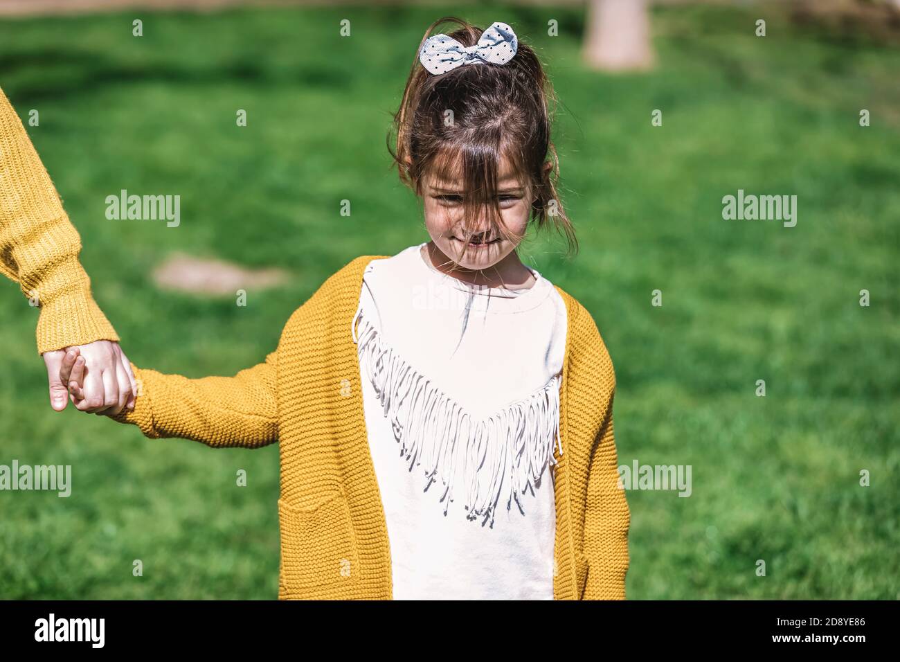 Sad girl is standing on green park holding mom hands Stock Photo - Alamy