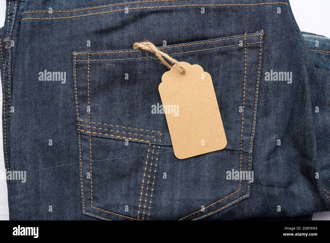 blank brown rectangular tag tied in the back pocket of blue folded ...