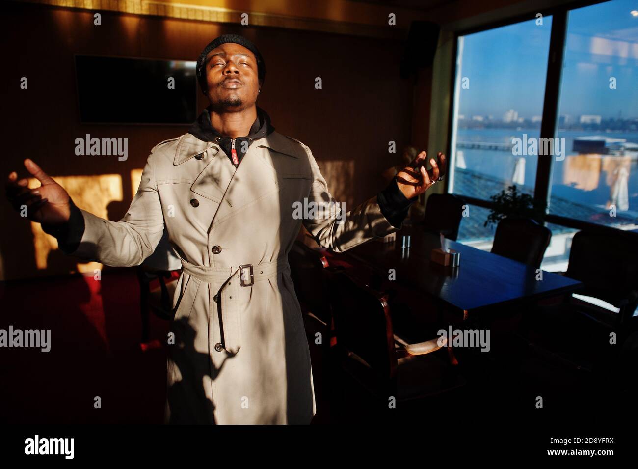 Handsome african american man posing inside room with sunlight shadows ...