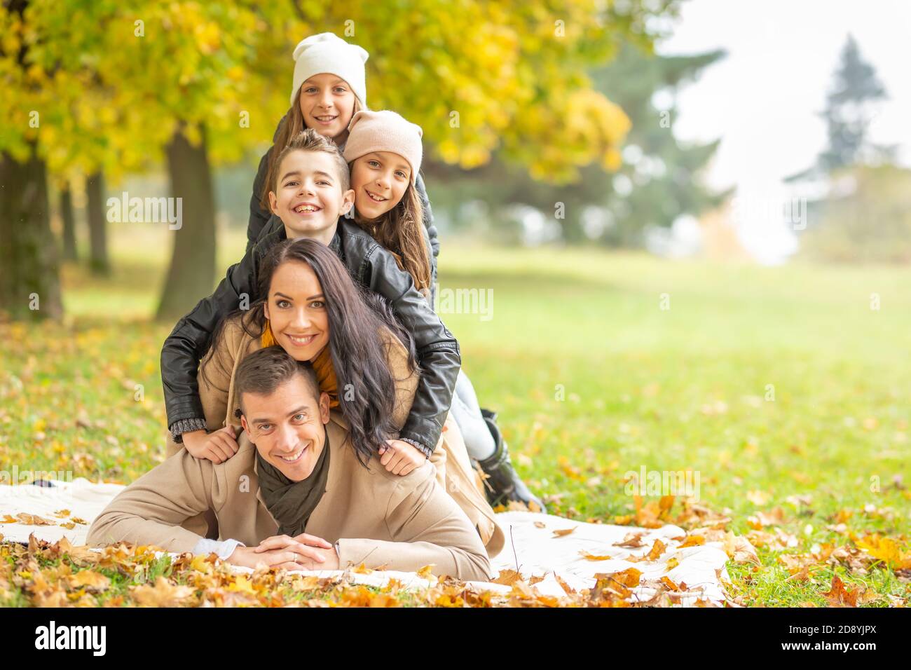 Family with children lying down on a blanket making a human pyramid in ...
