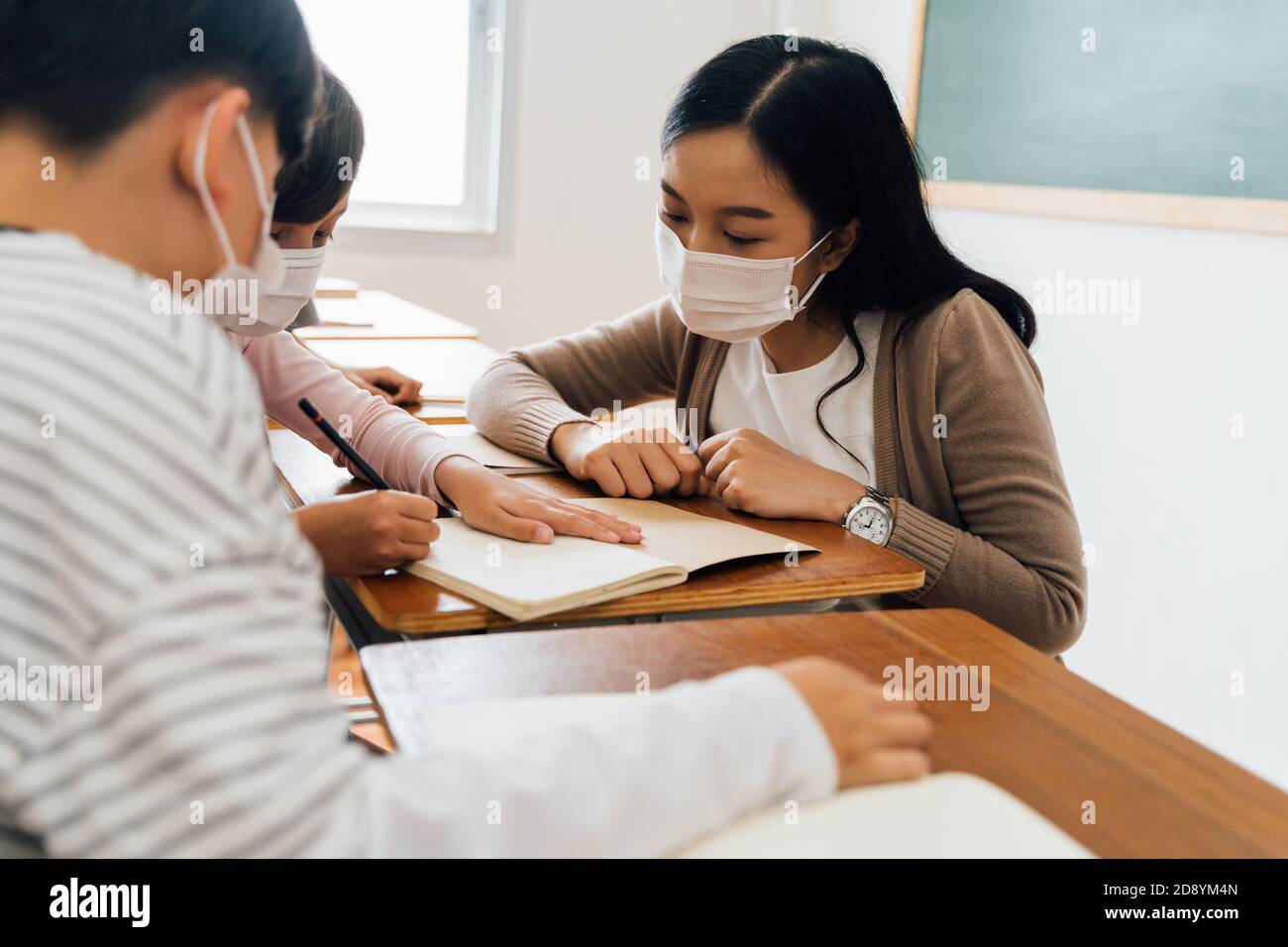 Close-up of Asian female teacher wearing a face mask in school building ...