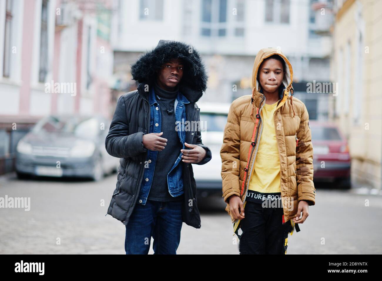Two african male friends walking together, wear on jackets with hoodie ...