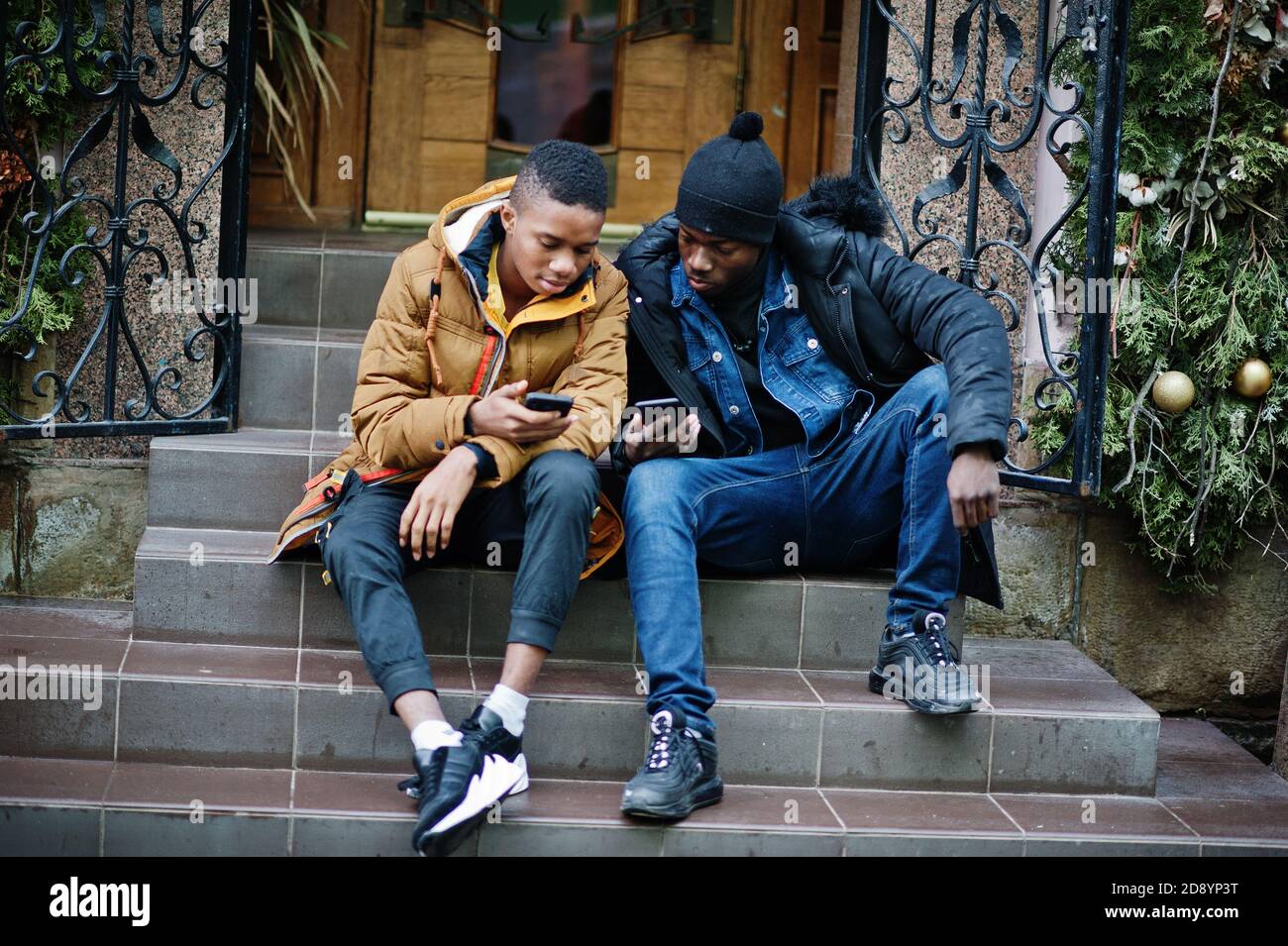 Two african male friends sitting and looking on phone together Stock ...