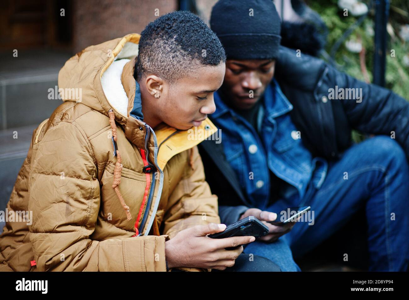 Two african male friends sitting and looking on phone together Stock ...