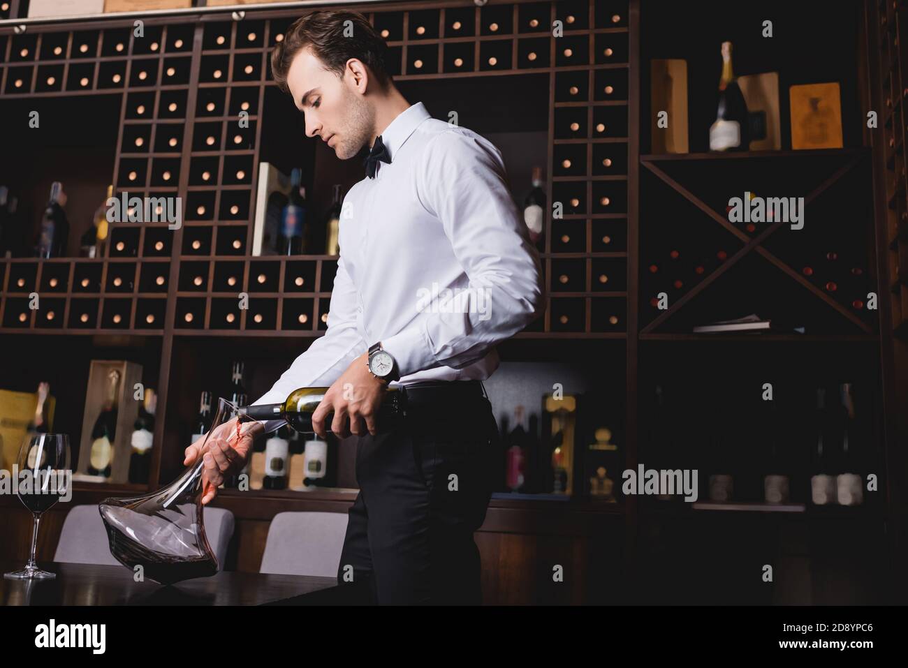 Sommelier in formal wear and bow tie pouring wine in decanter in ...