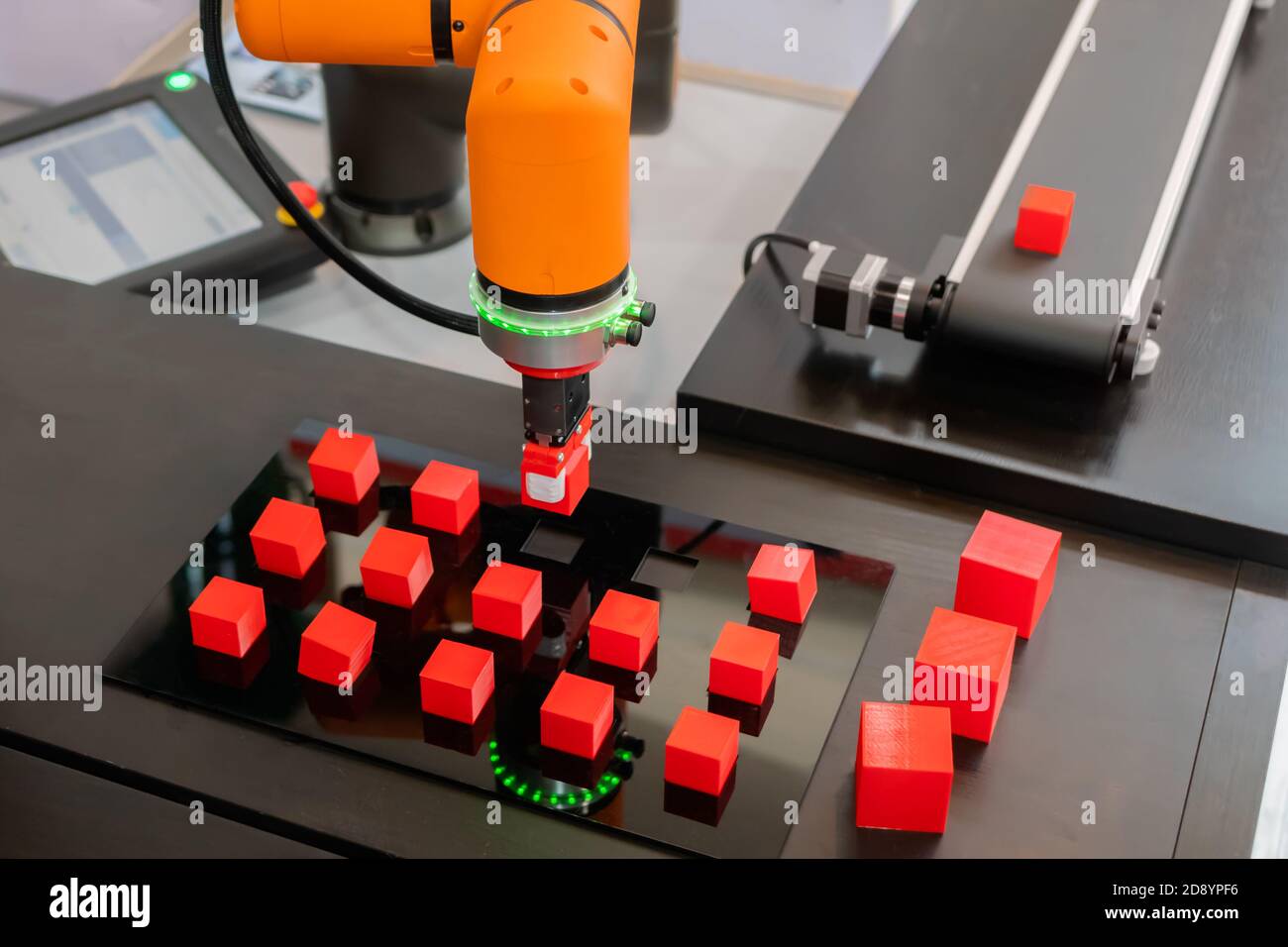Pick and place robotic clamp arm manipulator moving red toy blocks at modern robot exhibition ...