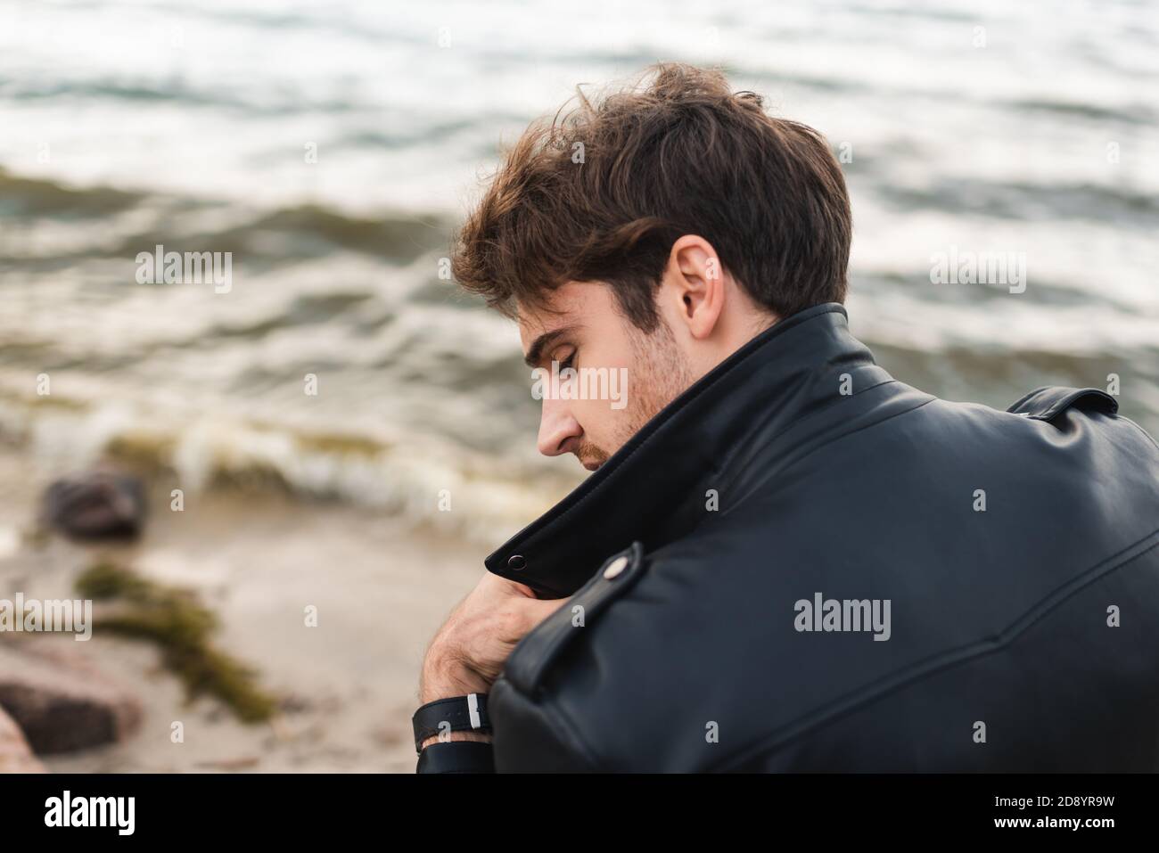 Back view of young man in black leather jacket on sea coast Stock Photo ...