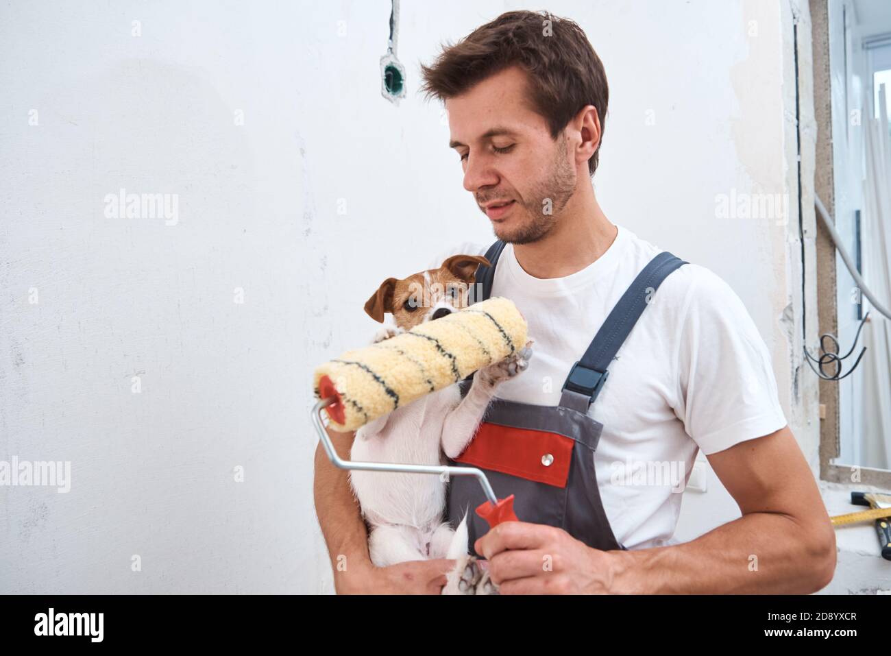 Man with his dog doing renovation work in the room. Good relationship ...