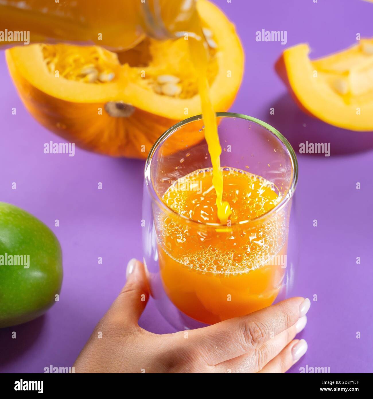 Fruit pumpkin apple carrot ginger on colored background hands juice ...