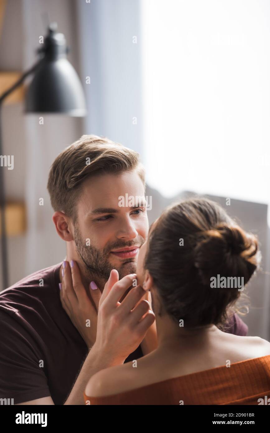 back view of young woman touching smiling man while looking at each ...