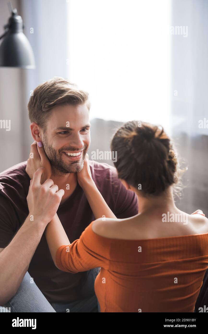 back view of young woman hugging neck of happy boyfriend while standing ...