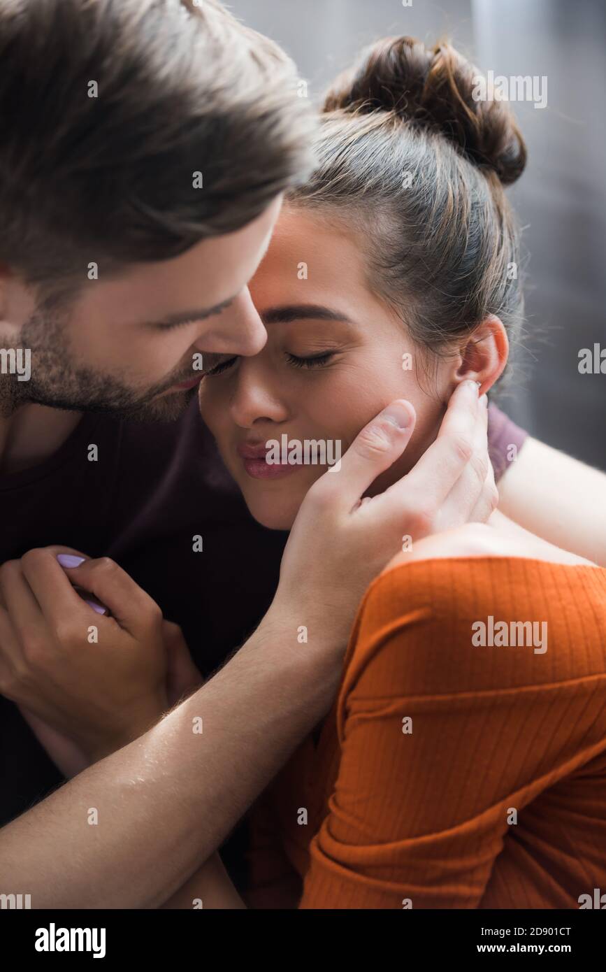 tender man hugging and touching face of depressed girlfriend at home ...