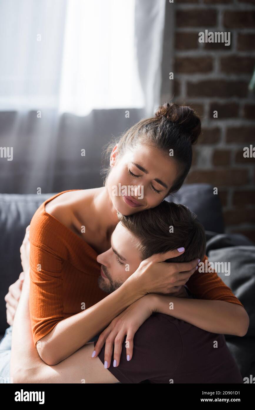 crying woman embracing beloved man while sitting on sofa Stock Photo ...