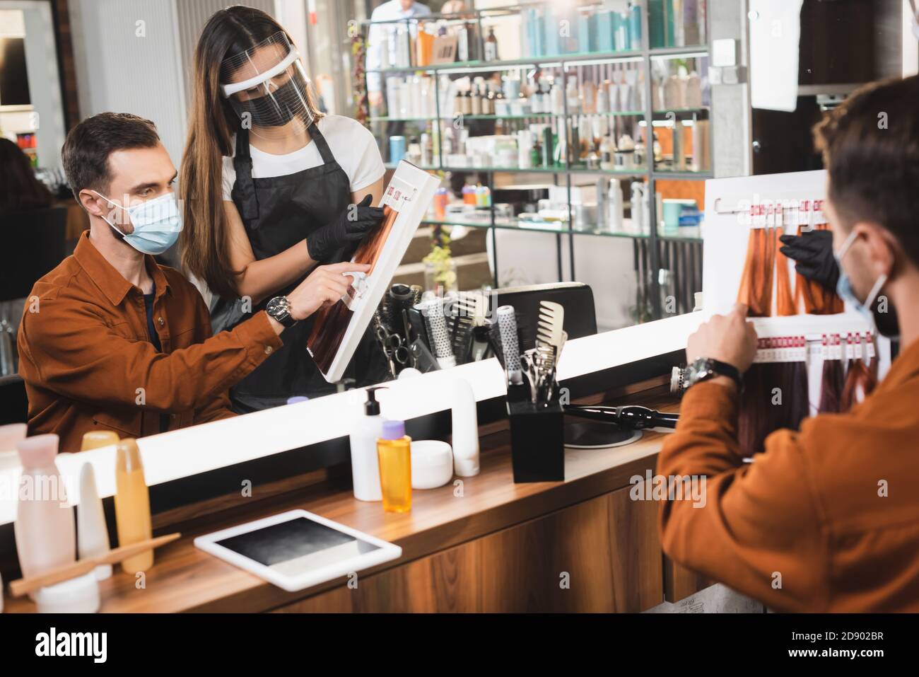 mirror reflection of hairdresser and client looking at hair color ...
