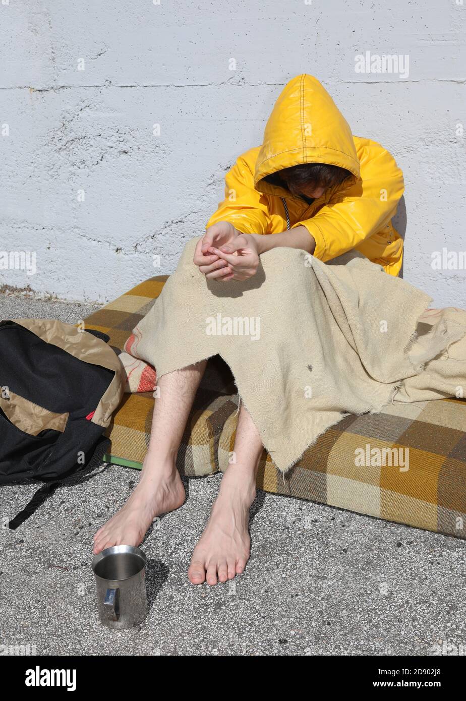 poor barefoot homeless man in a yellow hood asks for charity from ...
