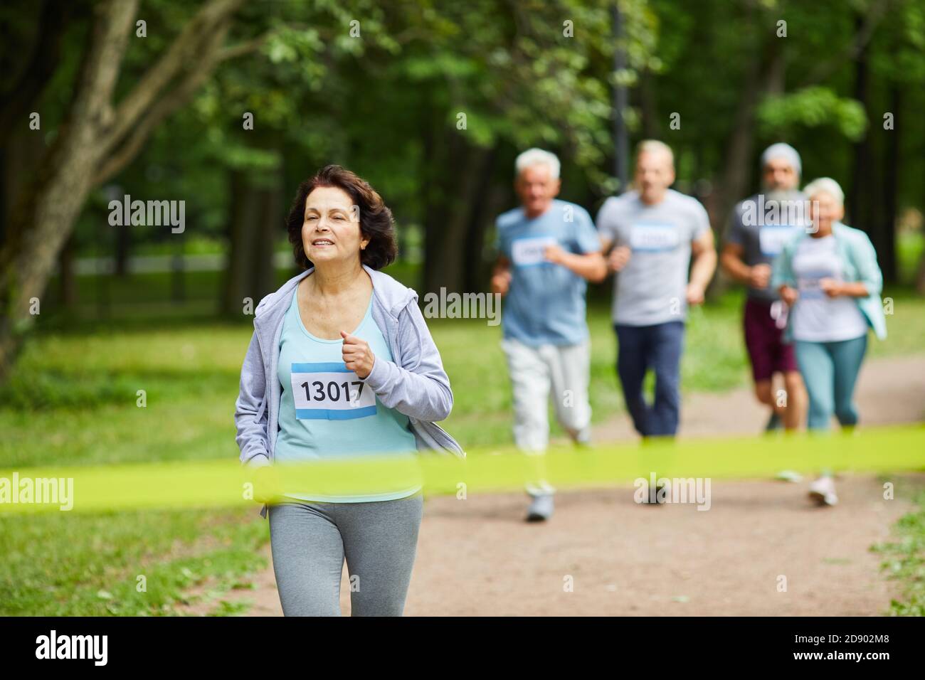 Active sporty mature woman with brown hair taking part in marathon race ...